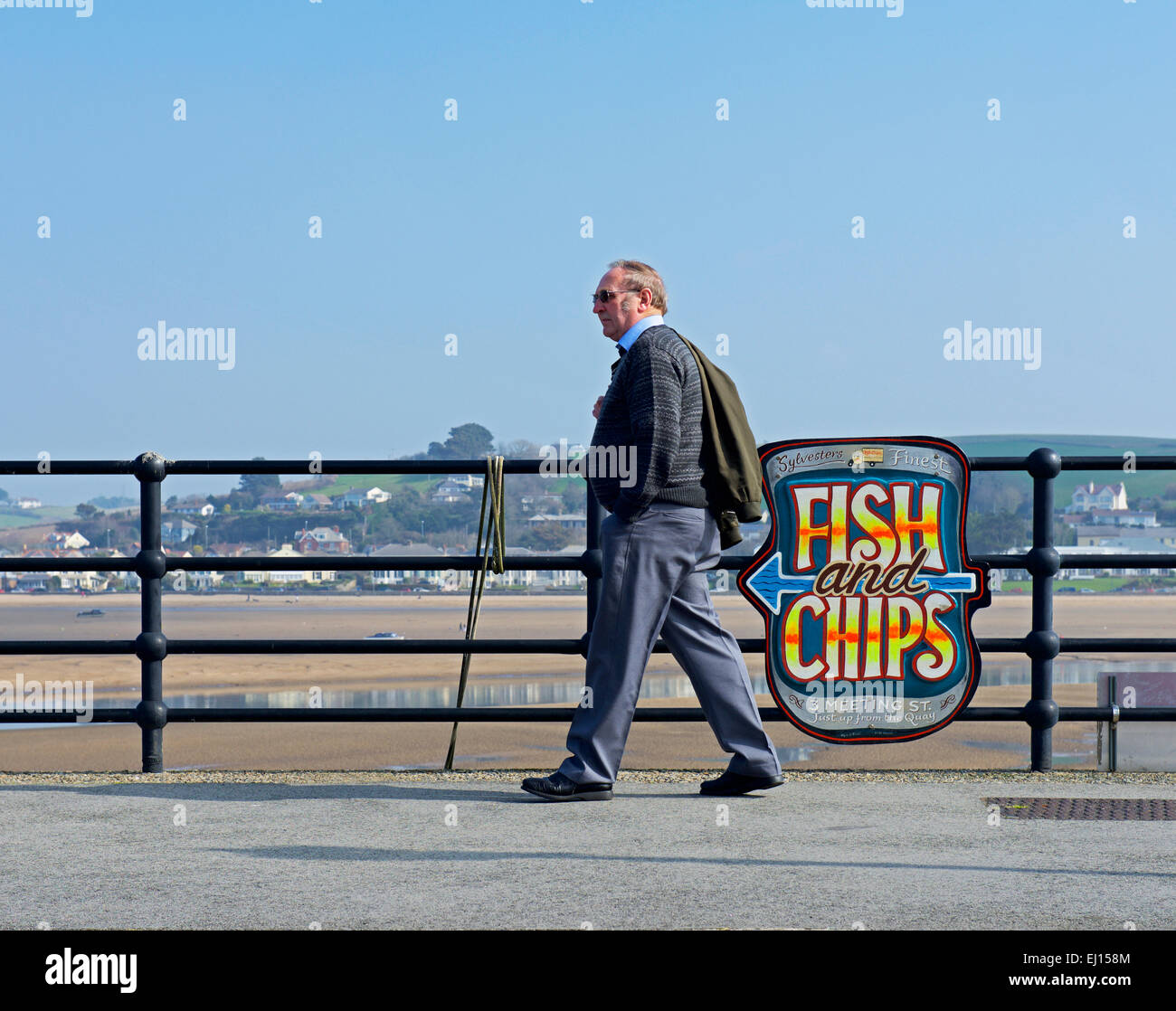 Man walking past sign - fish and chips - on the quayside in Appledore ...
