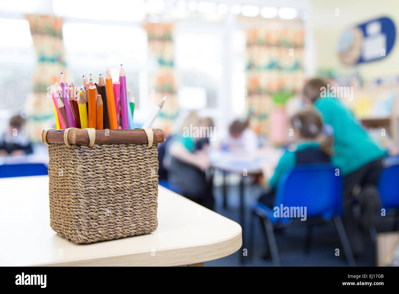 Pupils in a UK primary school classroom with a pot of coloured pencils ...