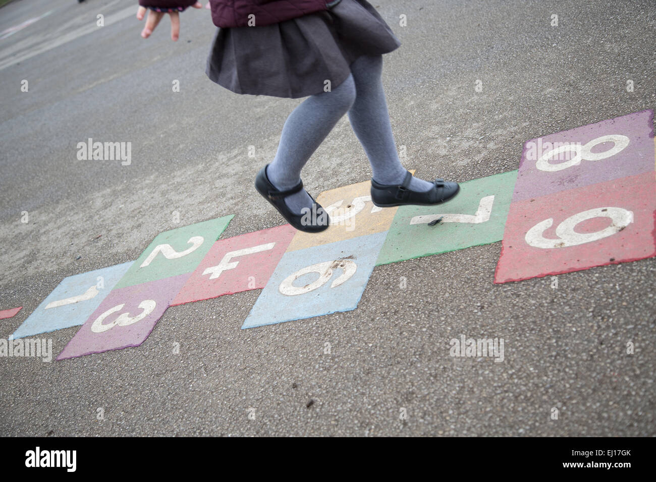 UK schoolgirl playing hopscotch in the playground of a UK primary ...