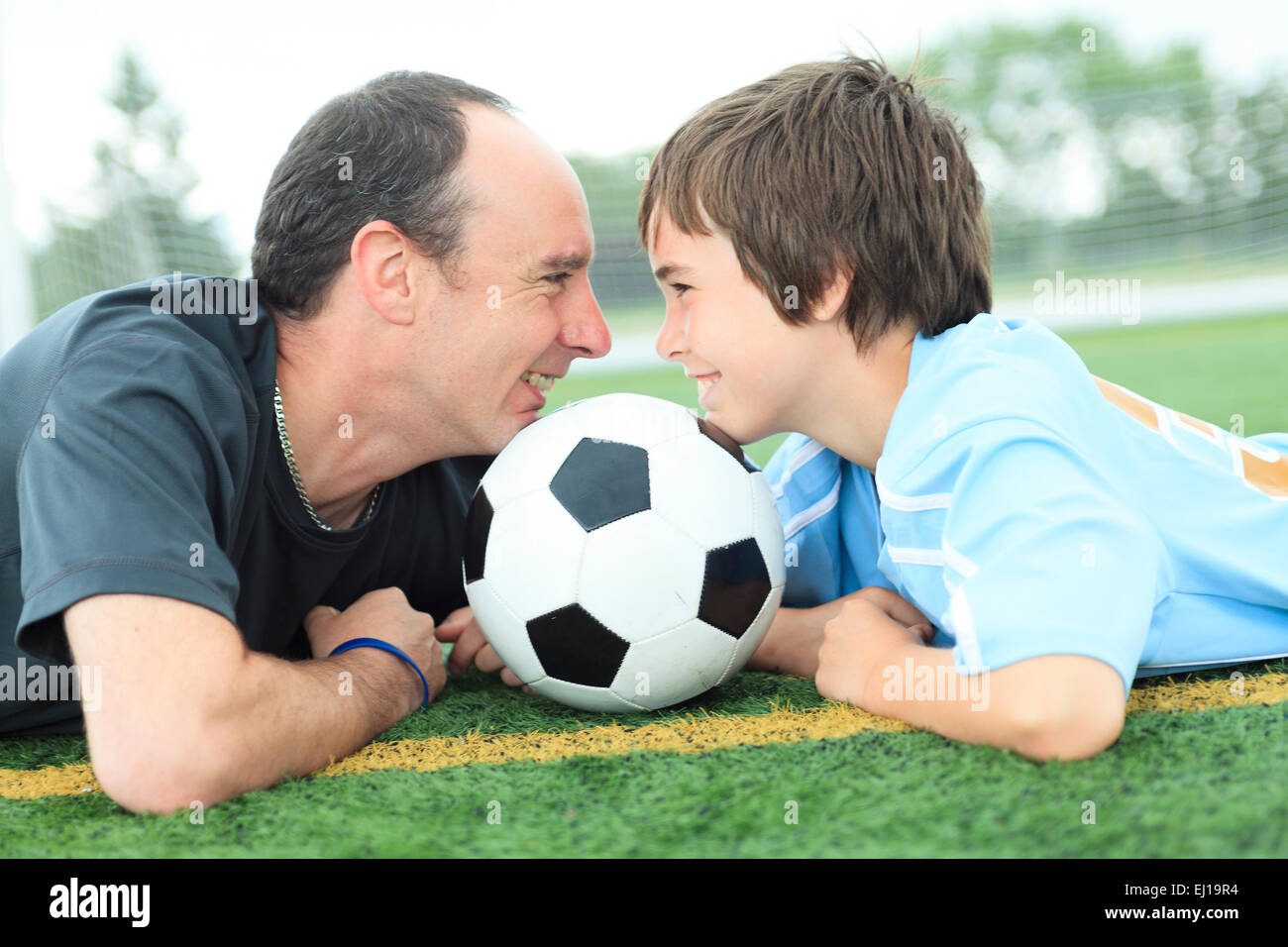 A young soccer player with father Stock Photo - Alamy