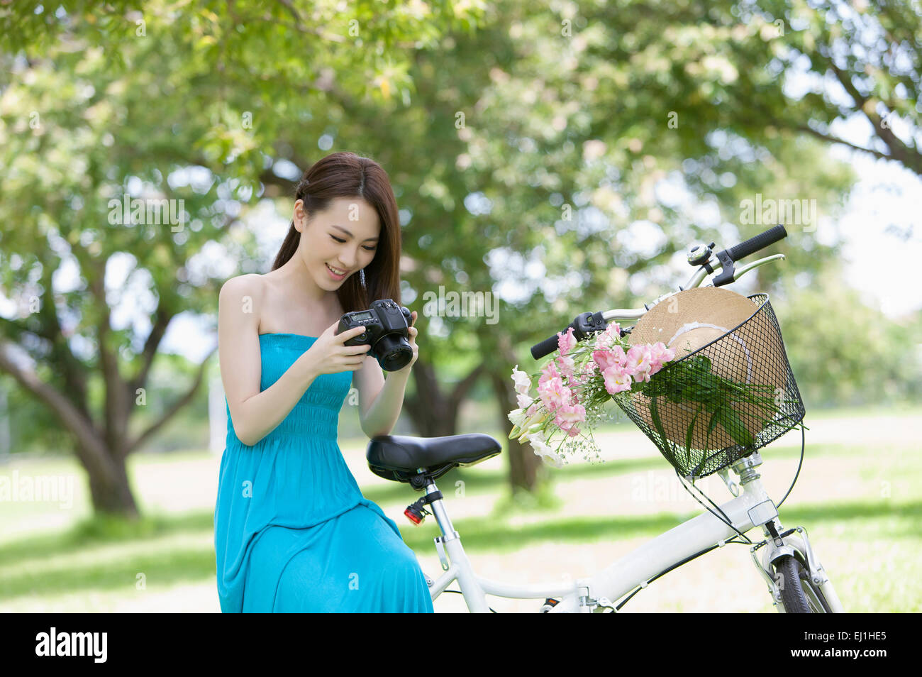 Young woman holding camera and looking down with smile Stock Photo - Alamy
