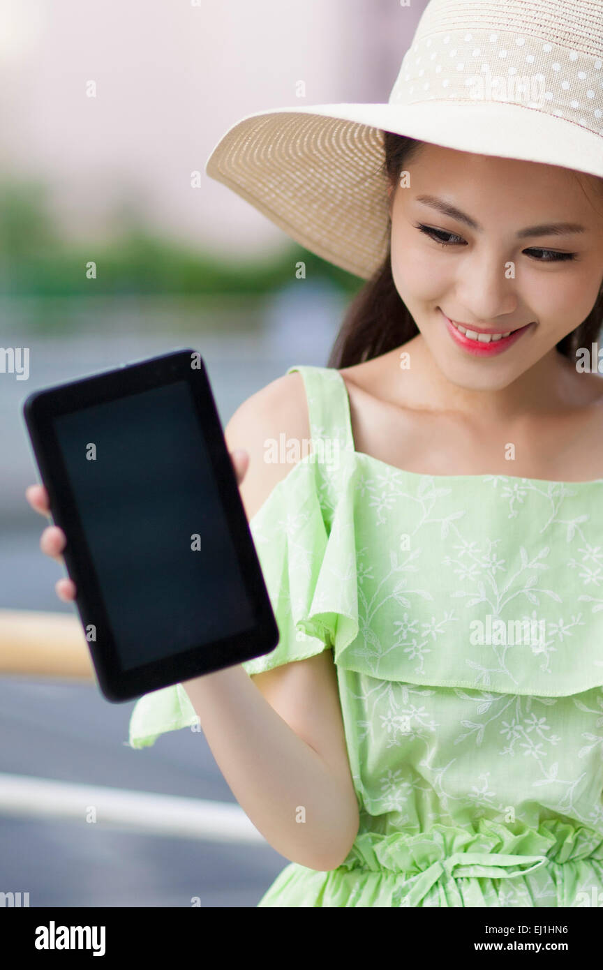 Young woman holding touch pad and looking down with smile Stock Photo ...