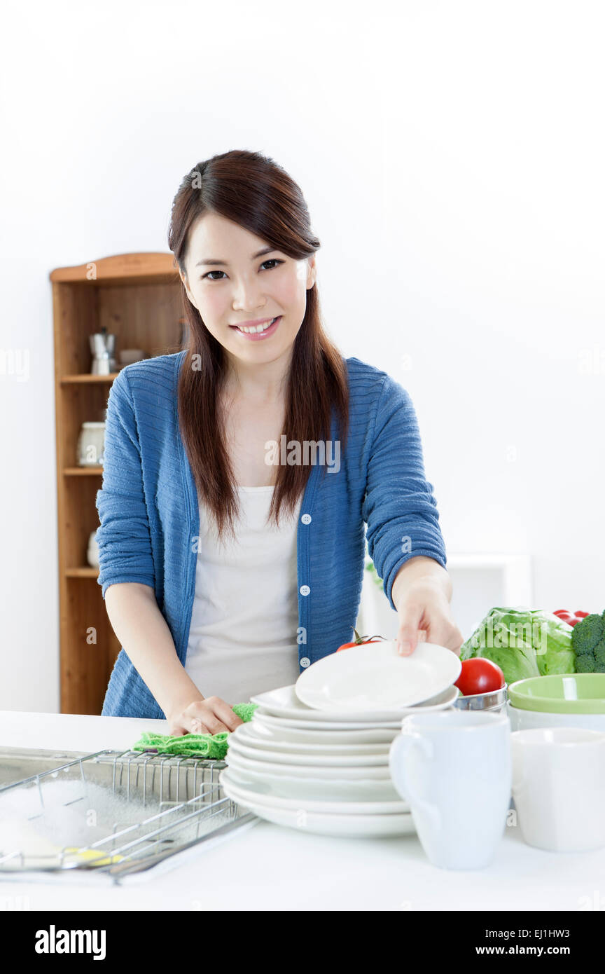 Young woman washing plates and smiling at the camera Stock Photo - Alamy