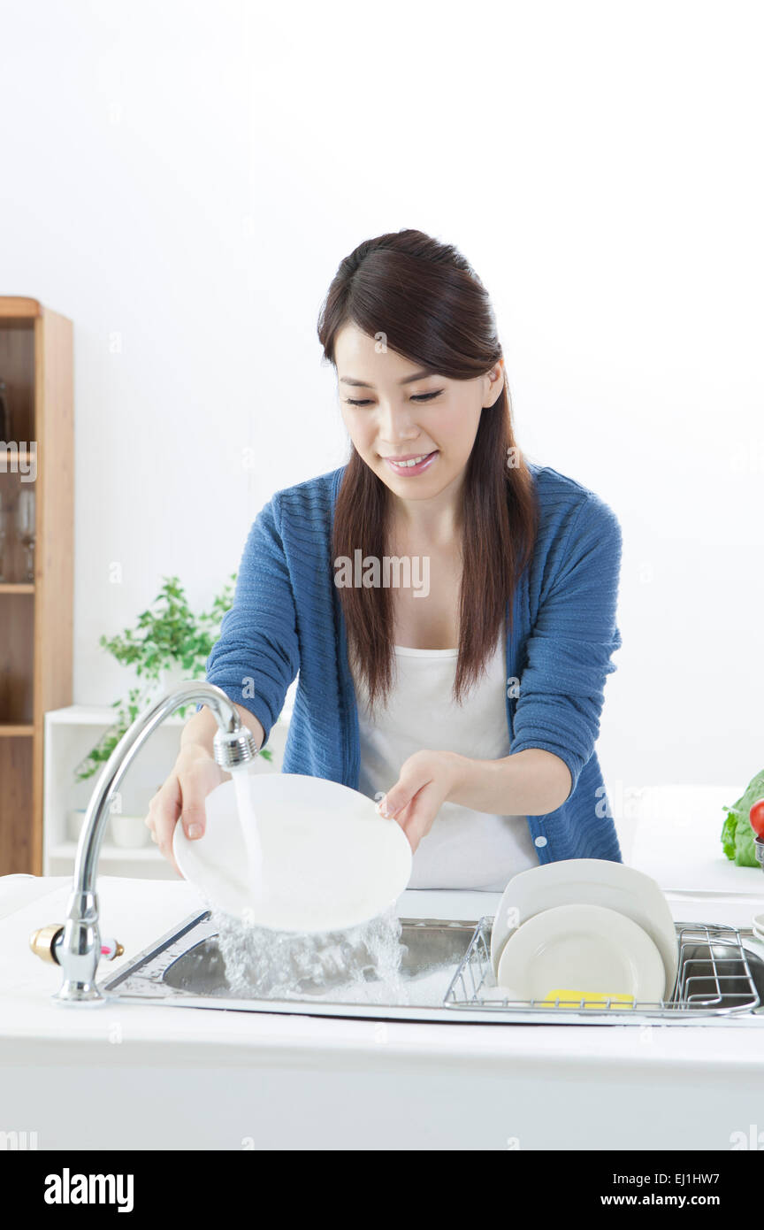 Young woman washing plates in the kitchen sink with smile Stock Photo ...