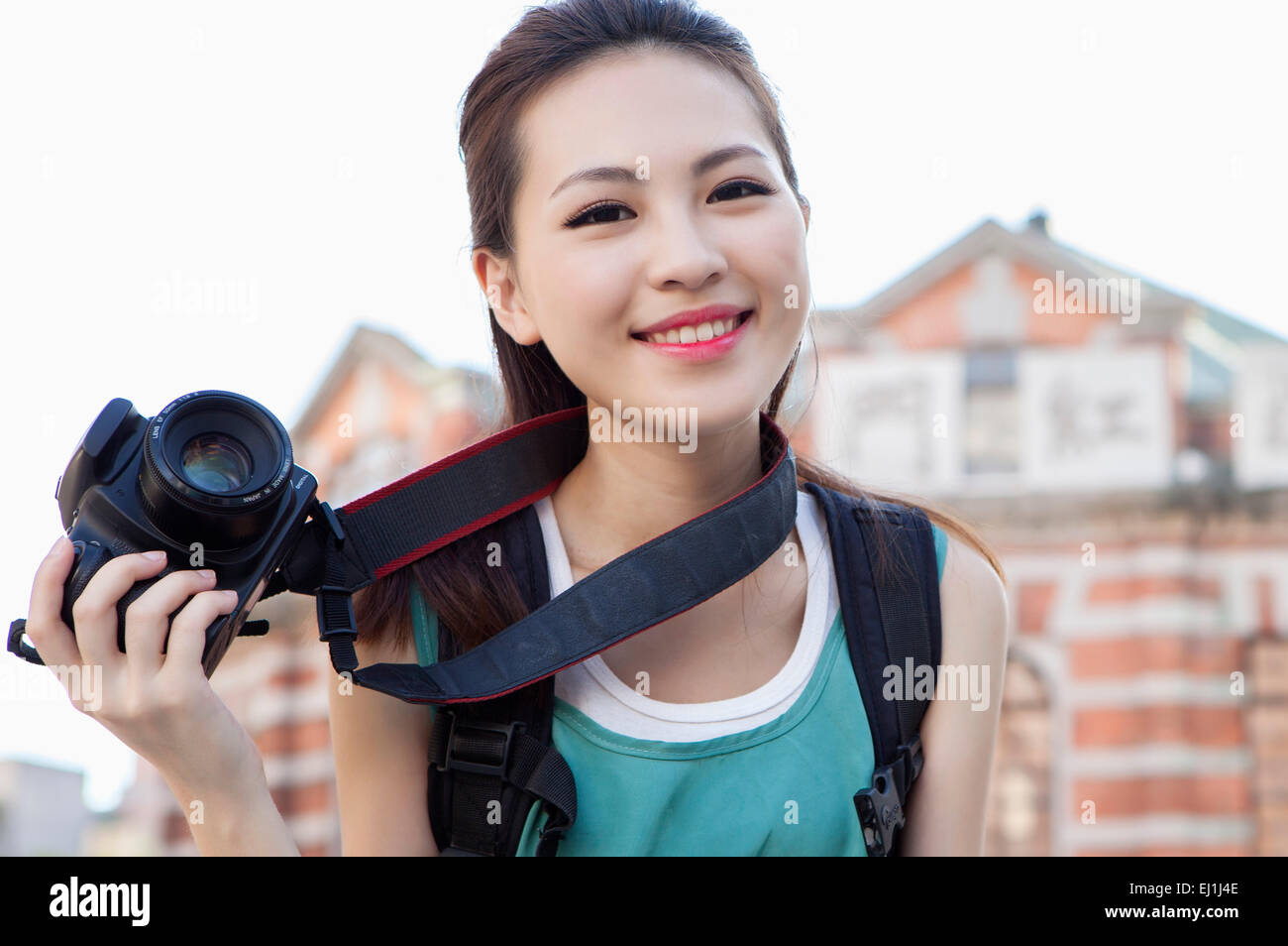Young woman holding digital camera and smiling at the camera Stock ...
