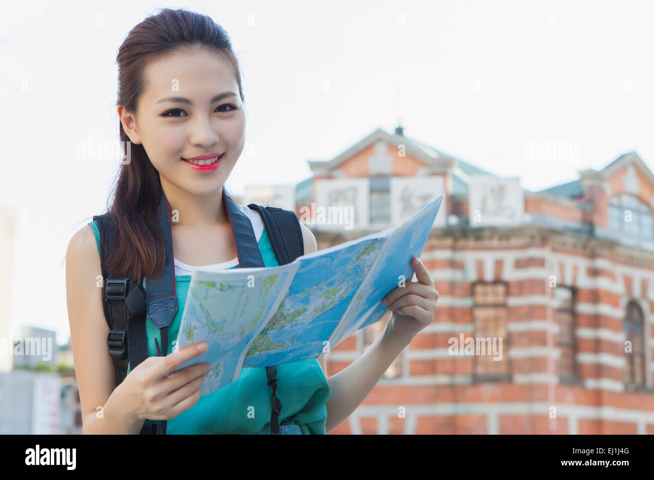 Young woman holding a map and smiling at the camera Stock Photo - Alamy