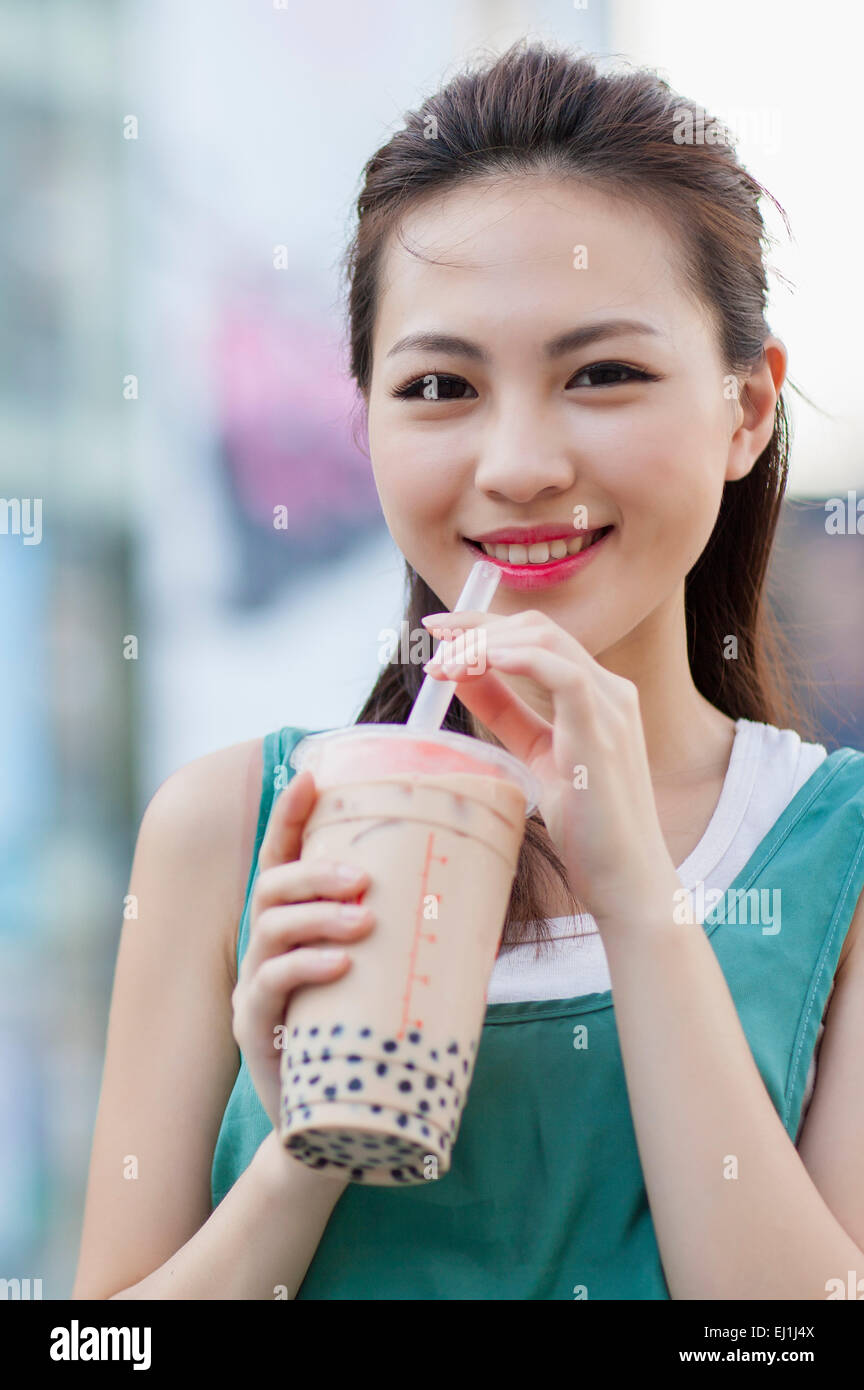 Young woman holding a bottle of bubble tea and smiling at the camera ...