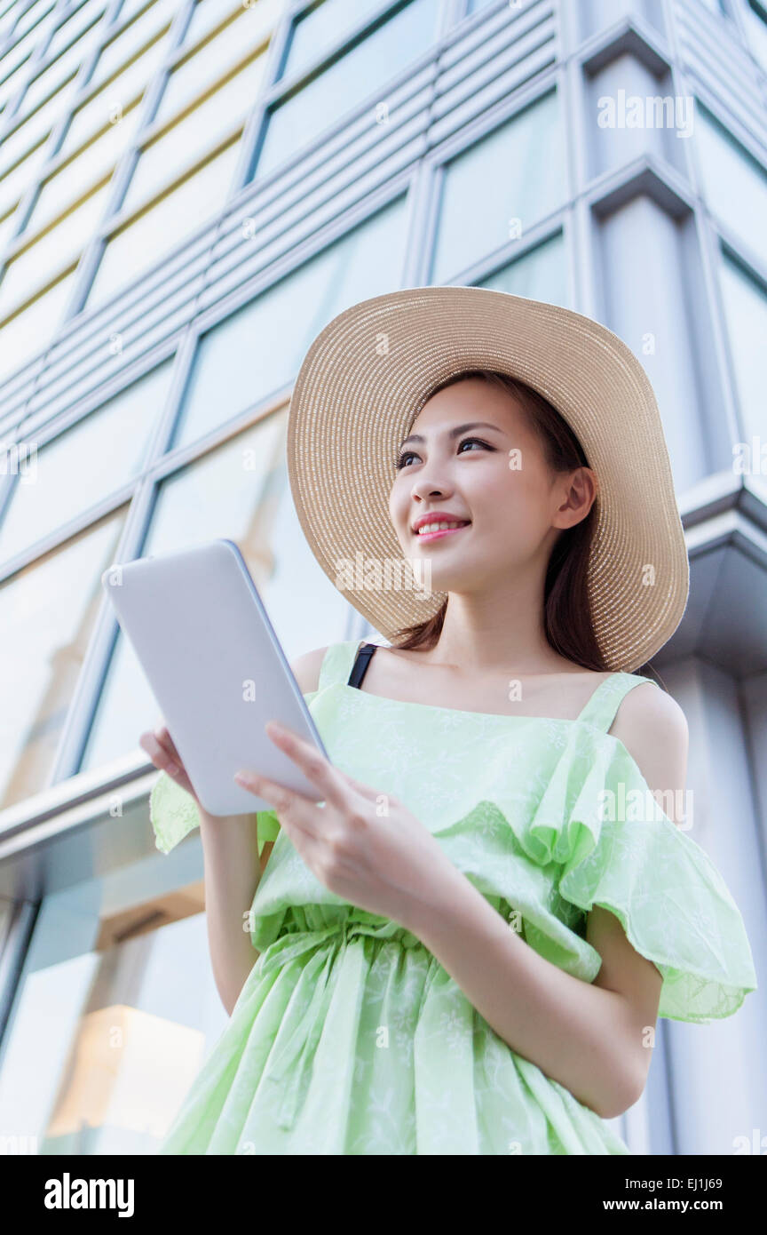 Young woman holding touch pad and looking away with smile Stock Photo ...
