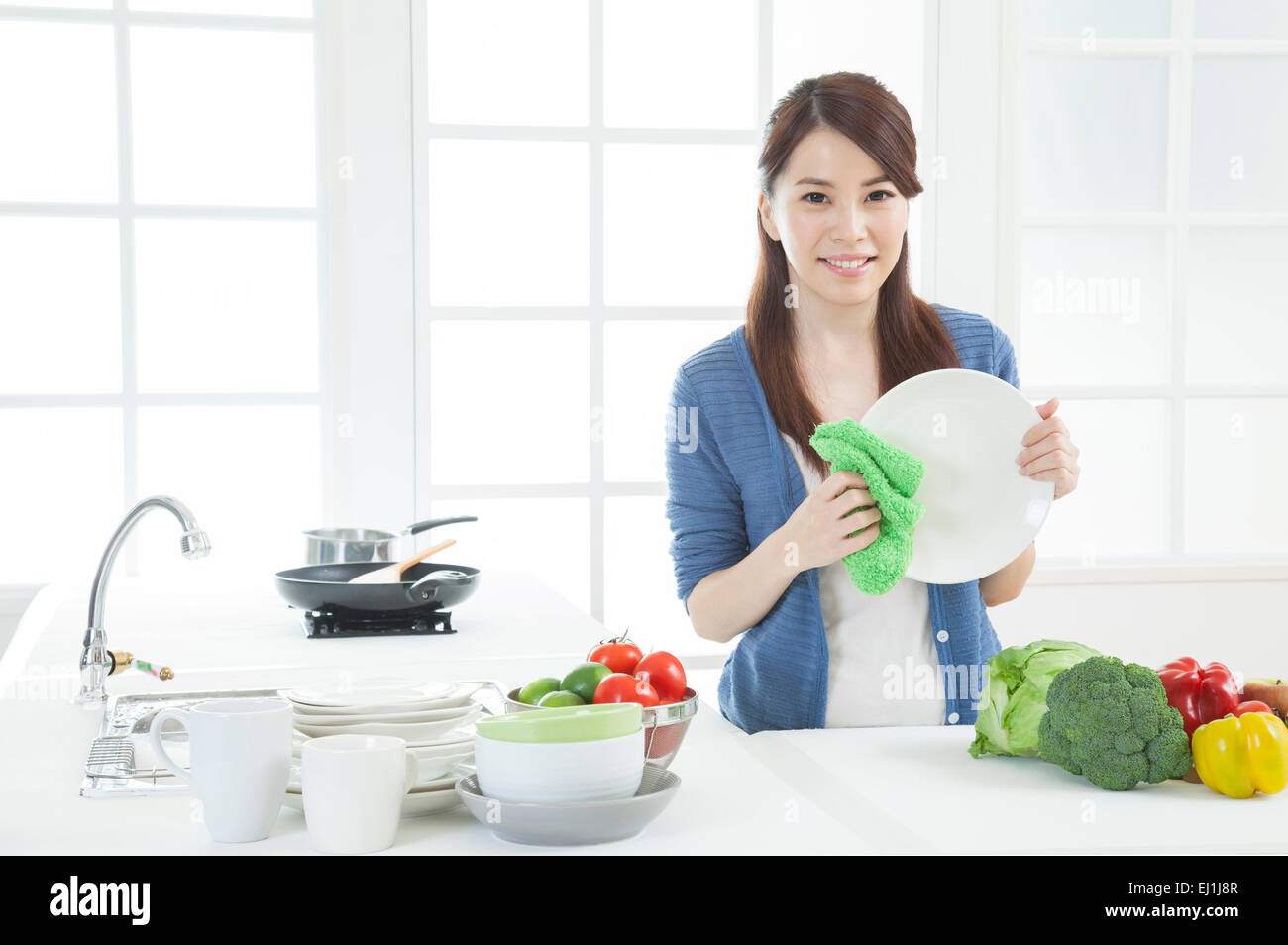 Young woman cleaning plates and smiling at the camera Stock Photo - Alamy