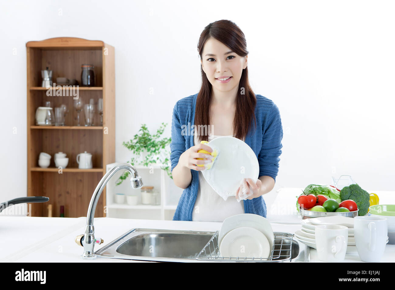 Young woman washing plates in the kitchen sink with smile Stock Photo ...