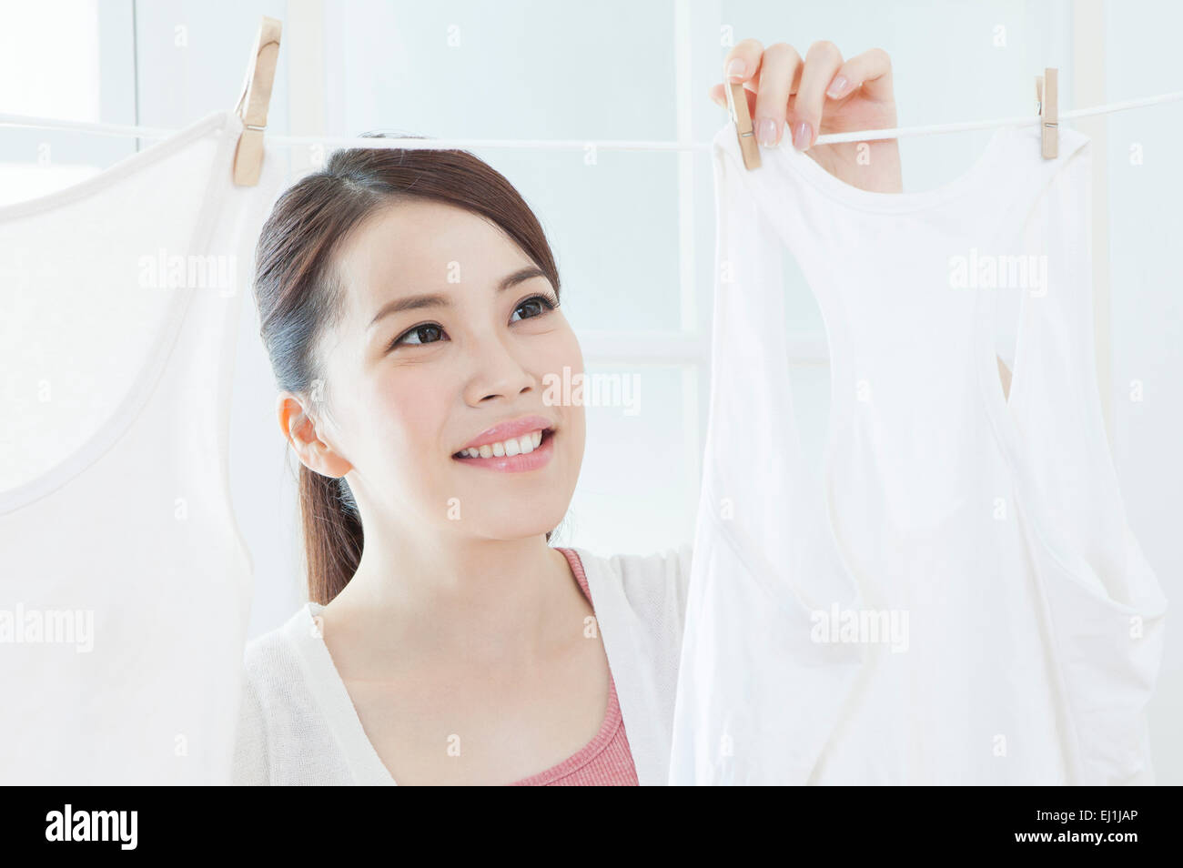 Young woman drying clothes and looking away with smile Stock Photo - Alamy