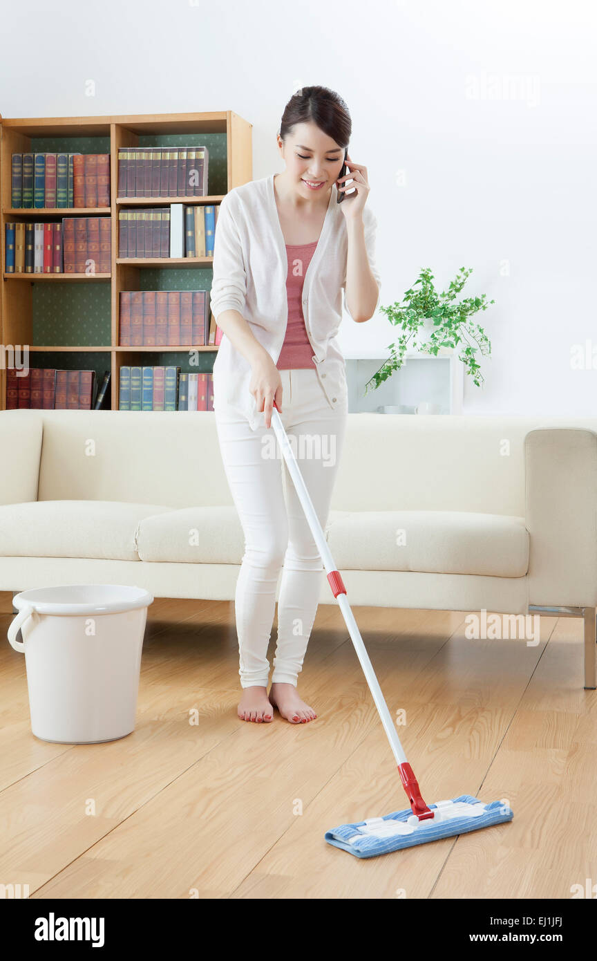 Young woman mopping the floor and on the phone Stock Photo - Alamy