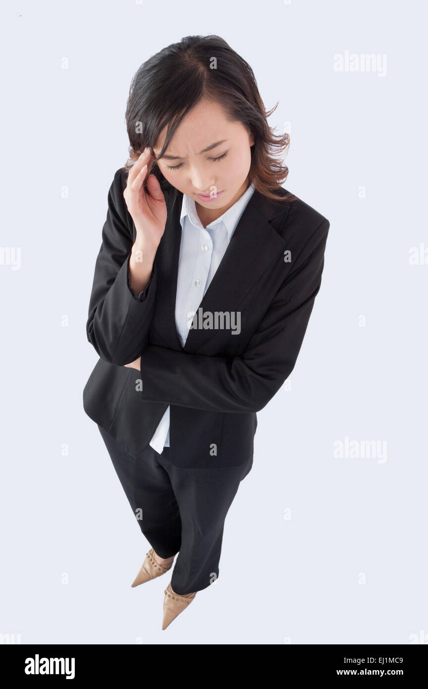 Young business woman standing and looking down with hand on head Stock ...