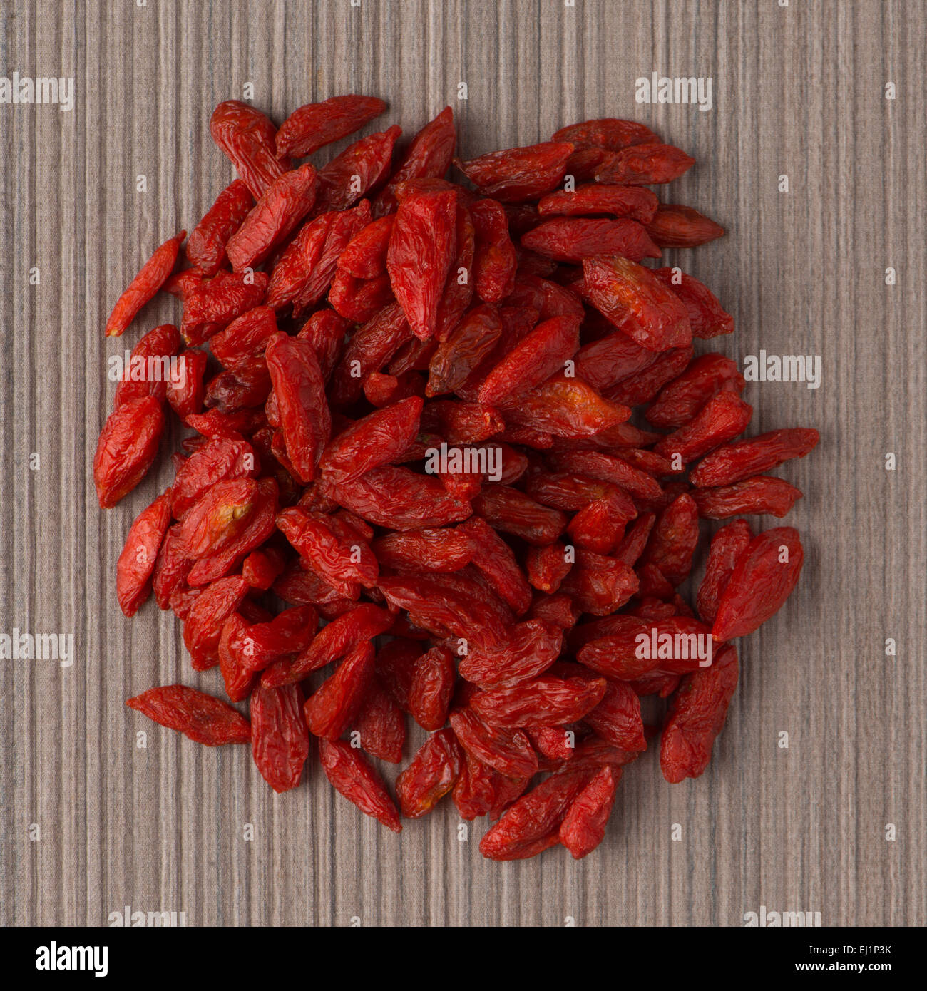 Top view of circle of dry red goji berries against brown vinyl ...