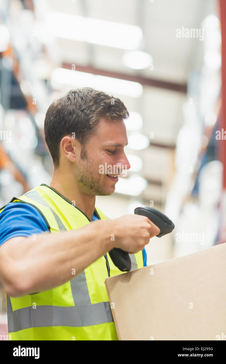 Smiling manual worker scanning package Stock Photo - Alamy