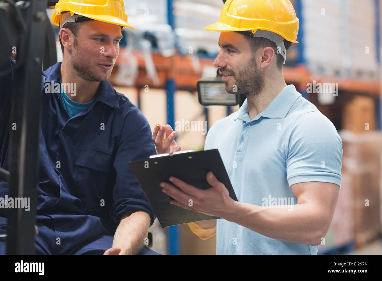Smiling warehouse workers talking together Stock Photo - Alamy