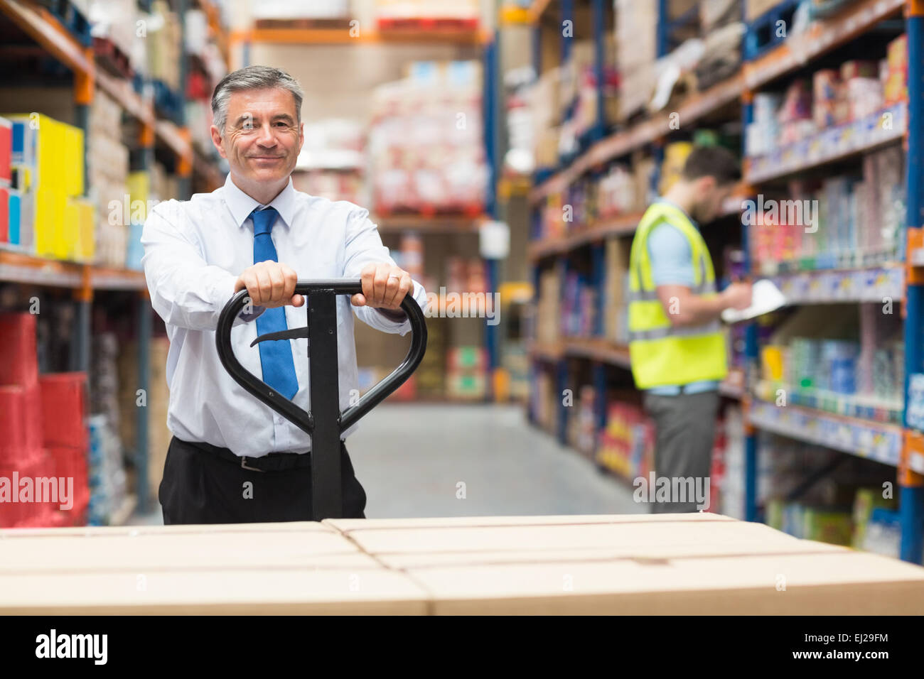 Manager pulling trolley with boxes in front of his employee Stock Photo ...