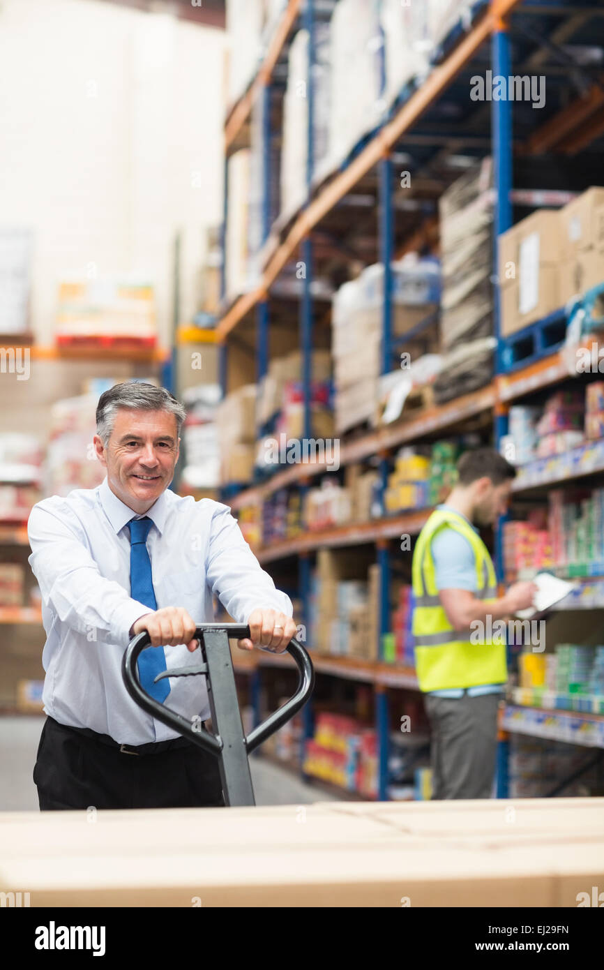 Manager pulling trolley with boxes in front of his employee Stock Photo ...