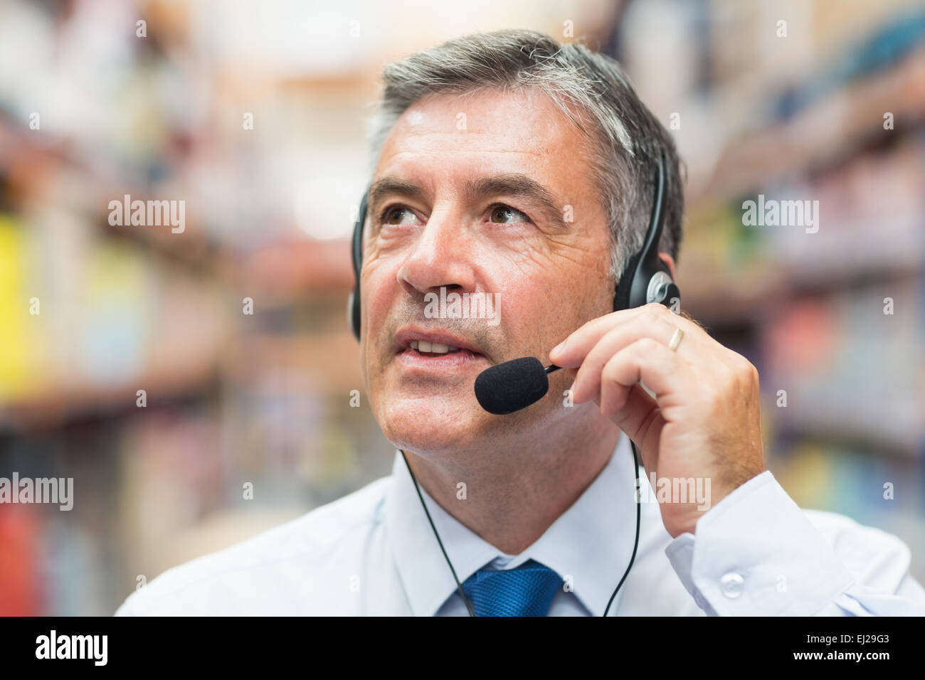 Warehouse manager giving orders on headset Stock Photo - Alamy