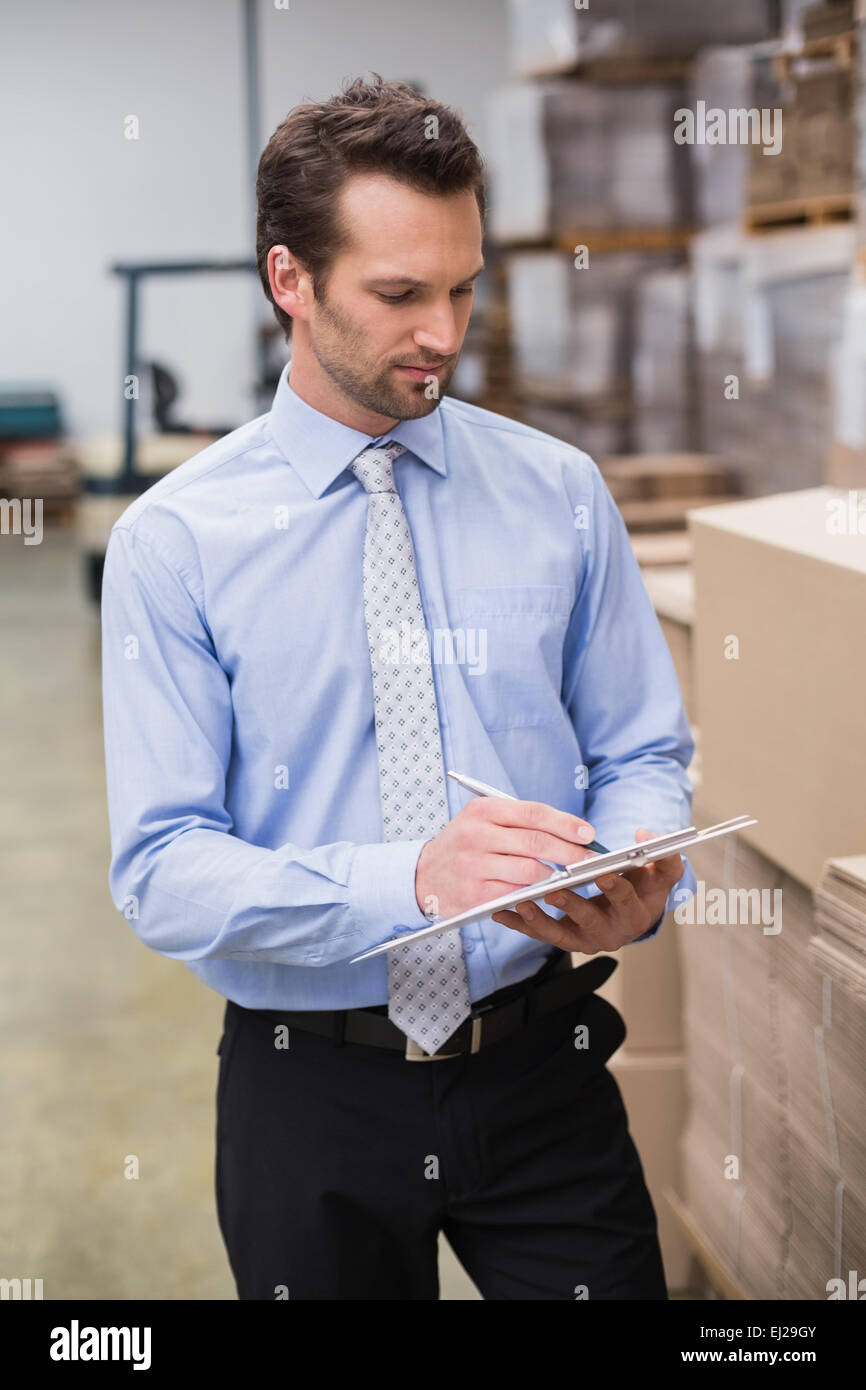Manager holding clipboard in warehouse Stock Photo - Alamy