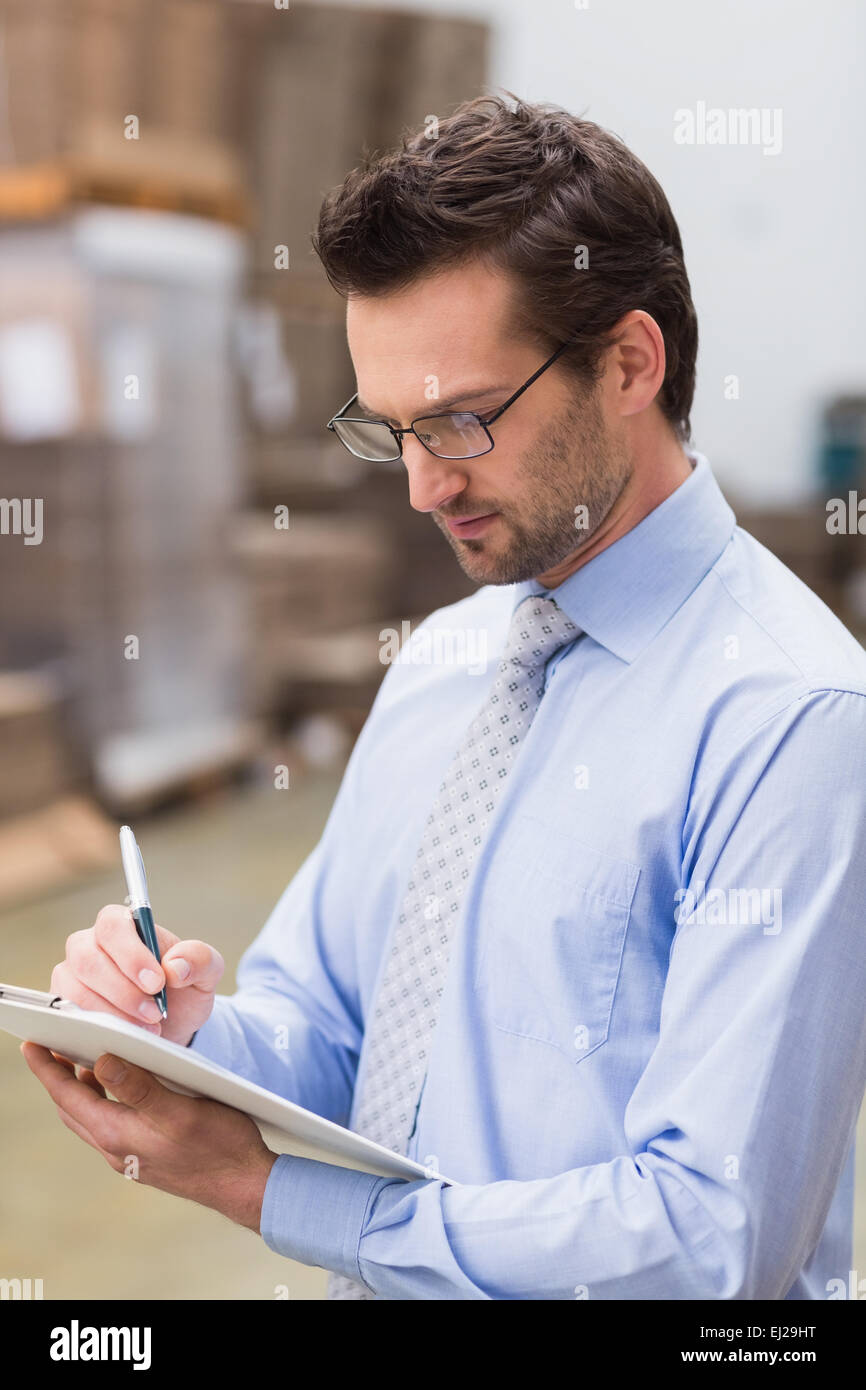Portrait of focused manager writing on his clipboard Stock Photo - Alamy