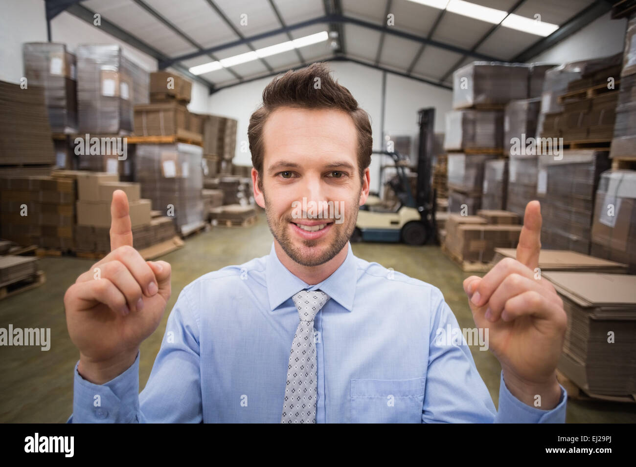 Smiling warehouse manager pointing up with finger Stock Photo - Alamy
