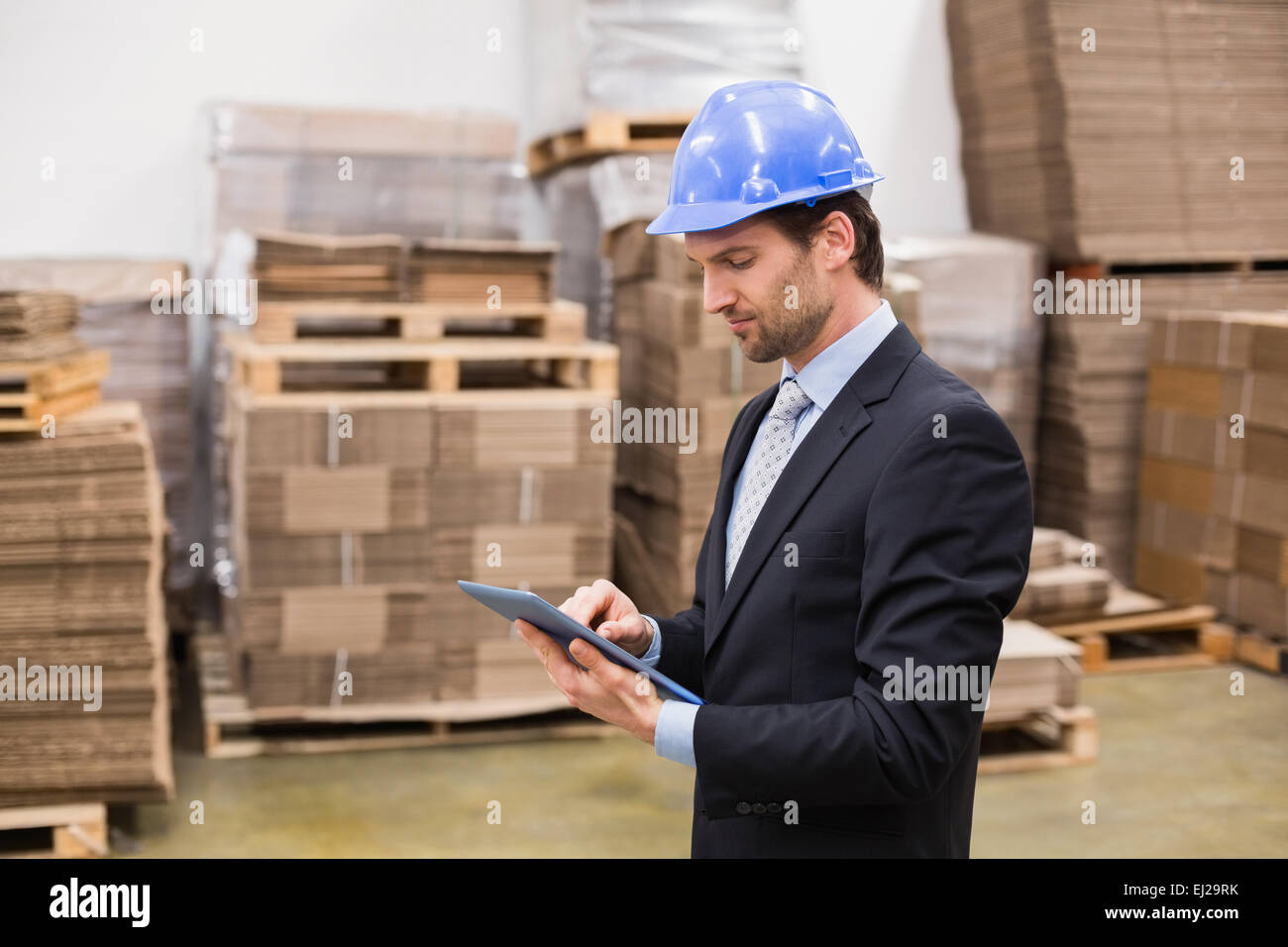 Warehouse manager wearing hard hat using tablet Stock Photo - Alamy