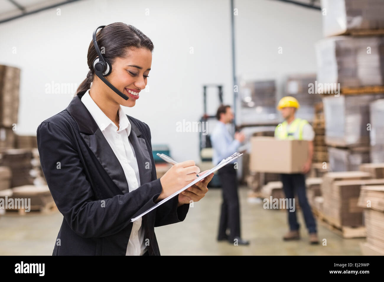 Warehouse manager writing on clipboard Stock Photo - Alamy