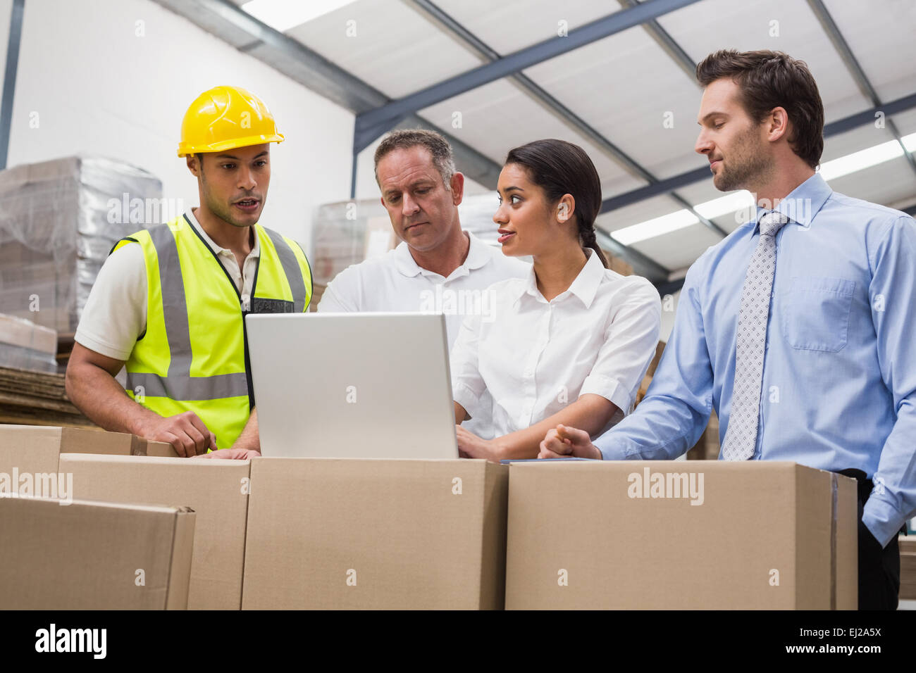 Warehouse managers and worker looking at laptop Stock Photo - Alamy