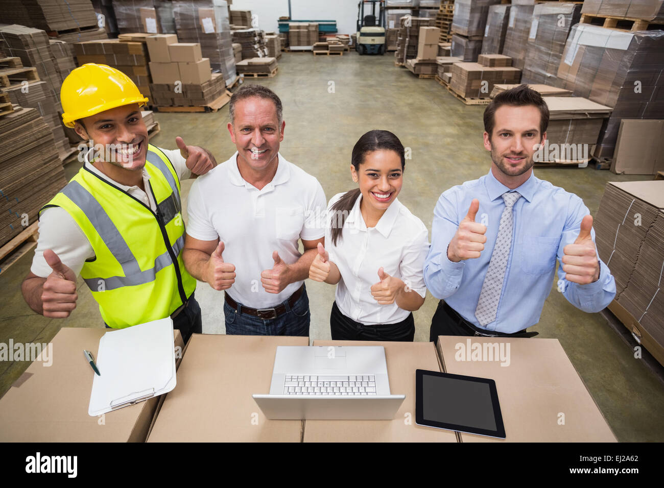 Warehouse team smiling at camera showing thumbs up Stock Photo - Alamy