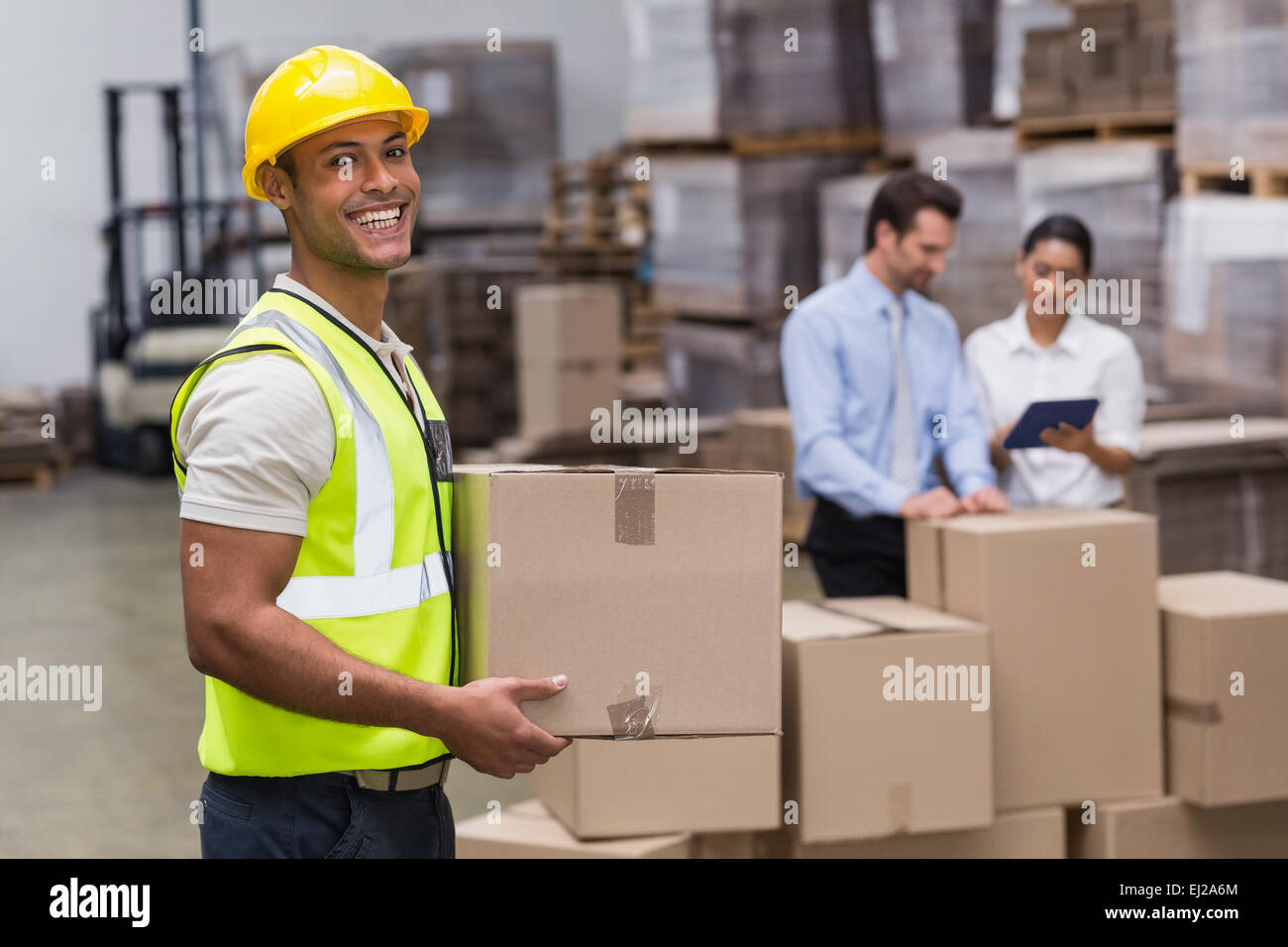 Worker carrying box in warehouse Stock Photo - Alamy