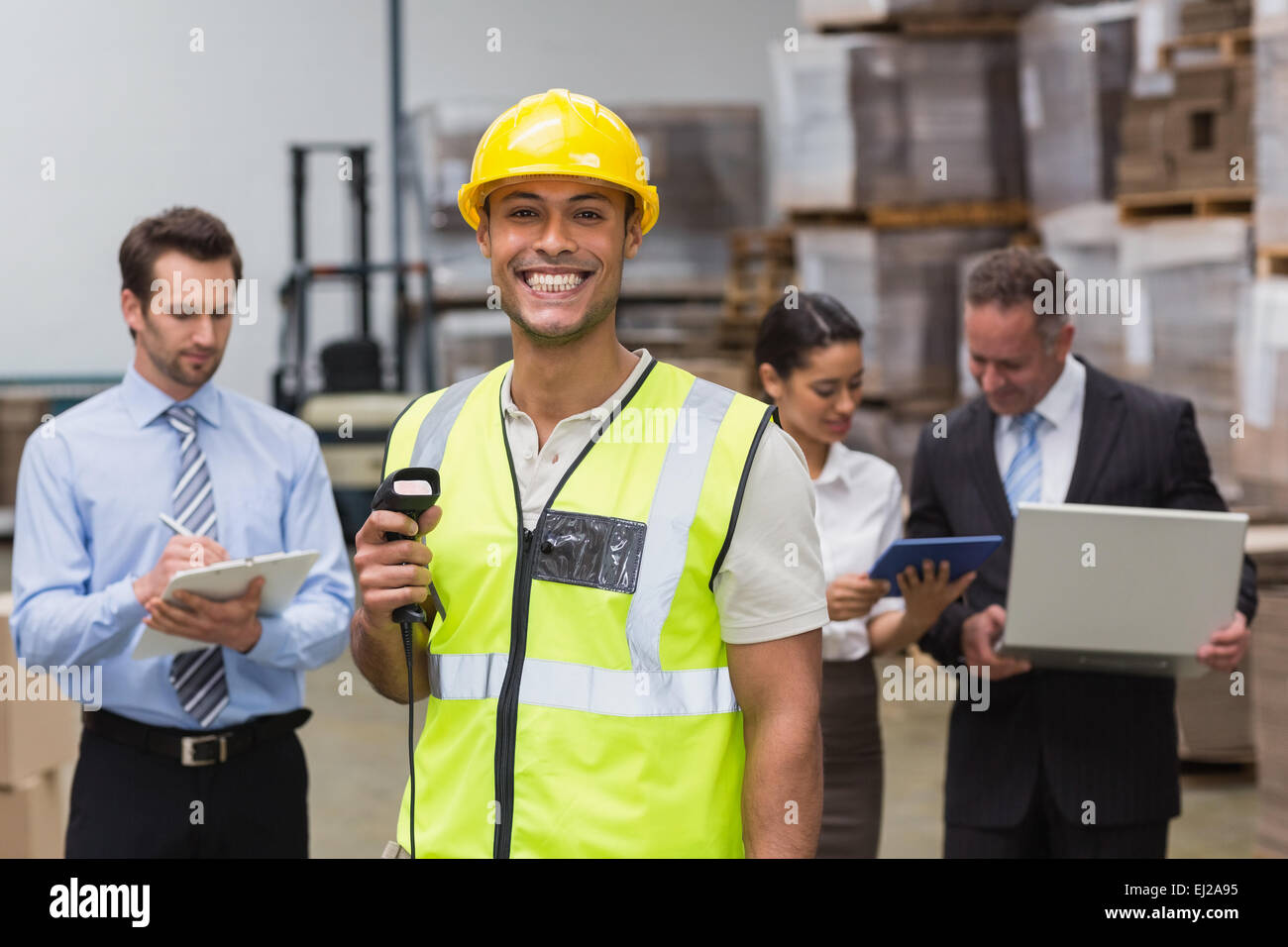 Worker standing with scanner in front of his colleagues Stock Photo - Alamy