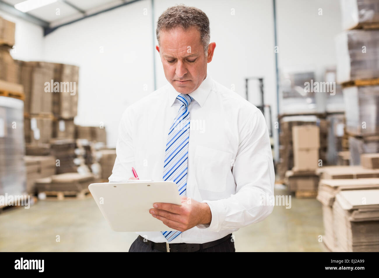 Serious boss writing on clipboard Stock Photo - Alamy