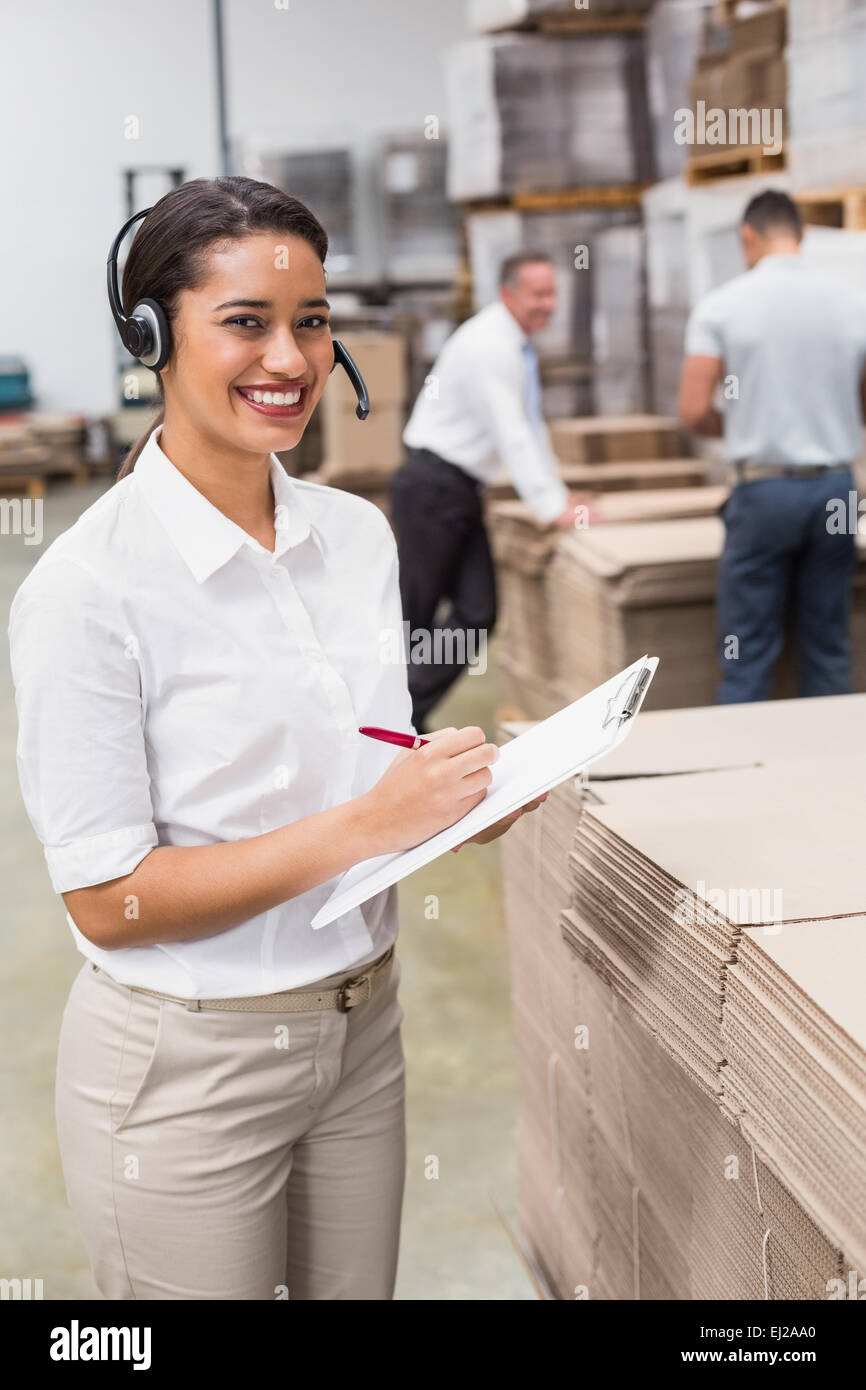 Warehouse manager writing on clipboard Stock Photo - Alamy