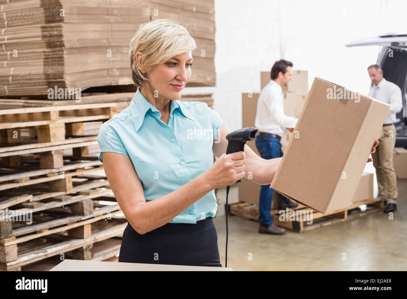 Smiling warehouse manager scanning package Stock Photo - Alamy