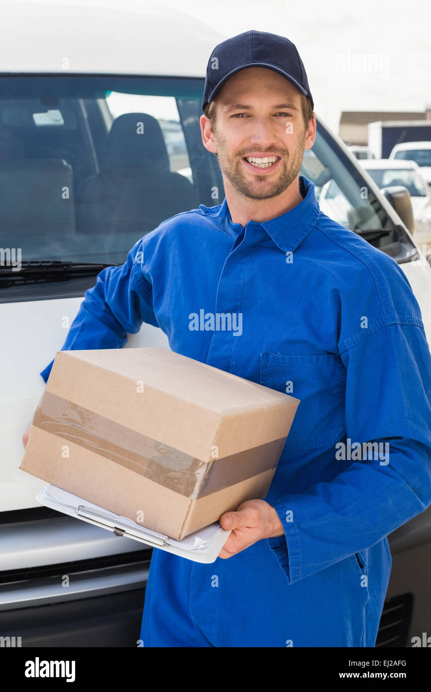Delivery driver smiling at camera by his van holding parcel Stock Photo ...