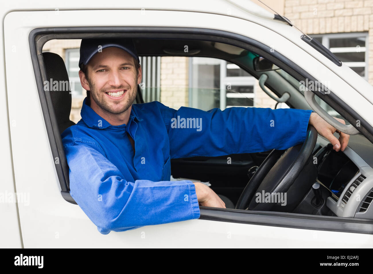 Delivery driver smiling at camera in his van Stock Photo - Alamy