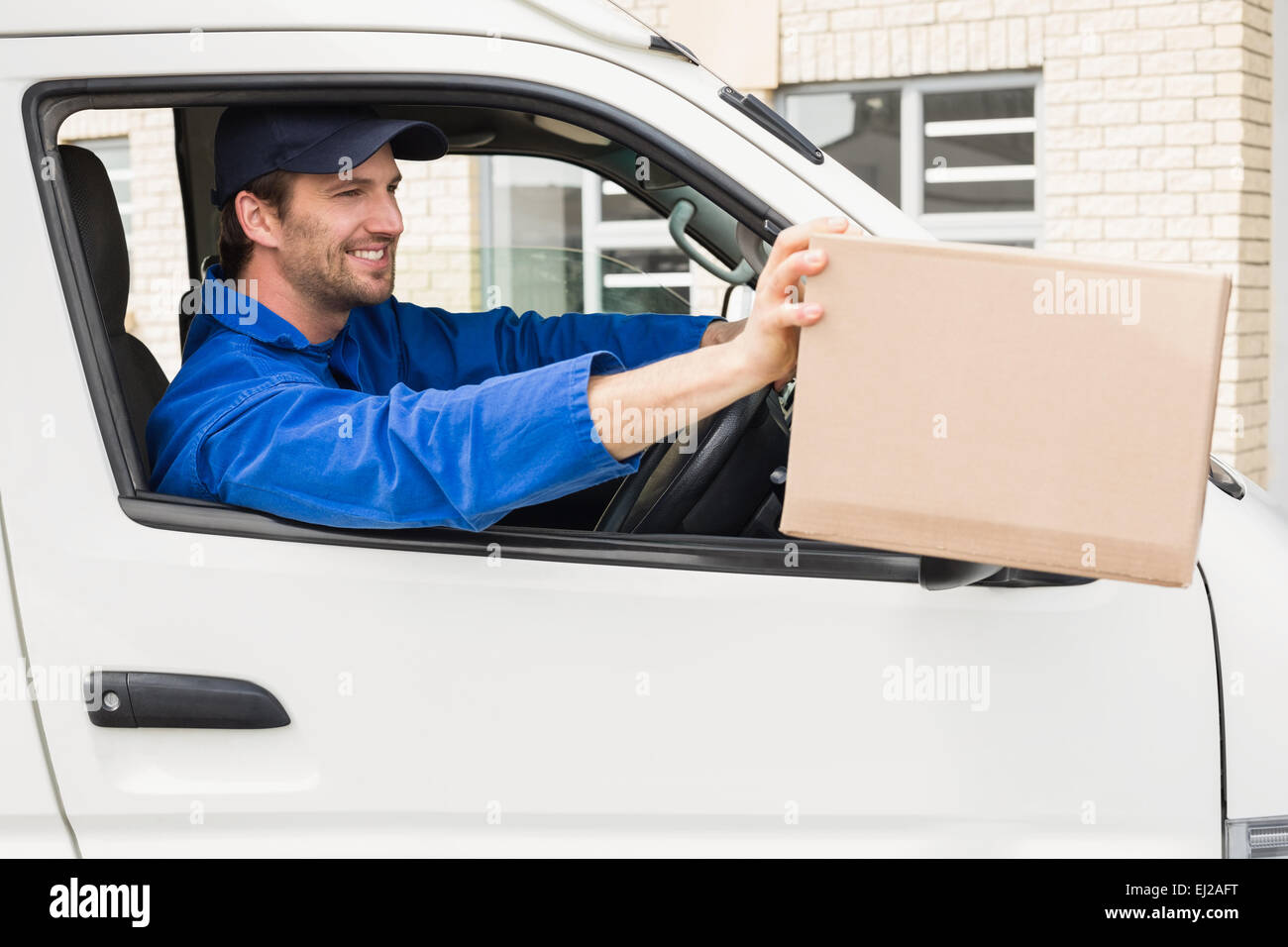 Delivery driver offering parcel from his van Stock Photo - Alamy
