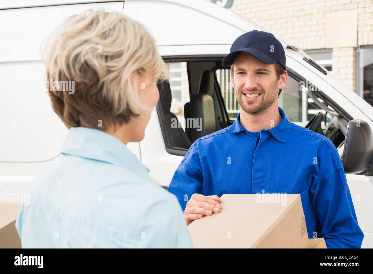 Delivery driver passing parcels to happy customer Stock Photo - Alamy