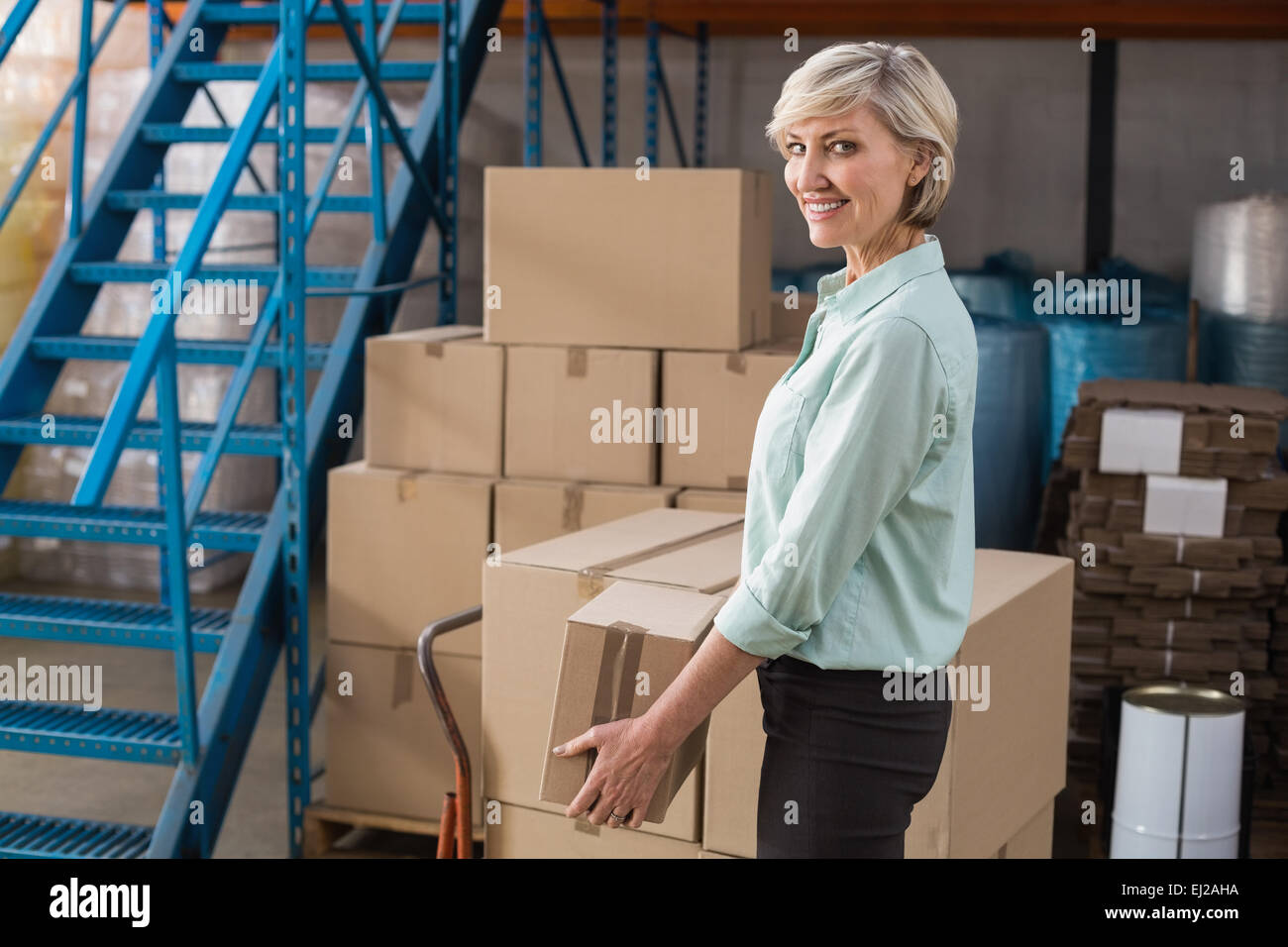 Smiling warehouse manager holding cardboard box Stock Photo - Alamy