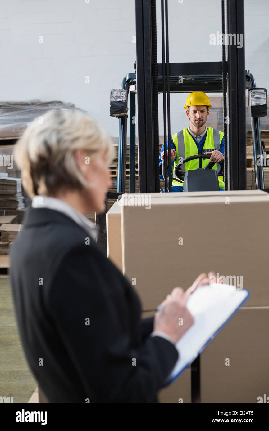 Warehouse manager writing on clipboard Stock Photo - Alamy