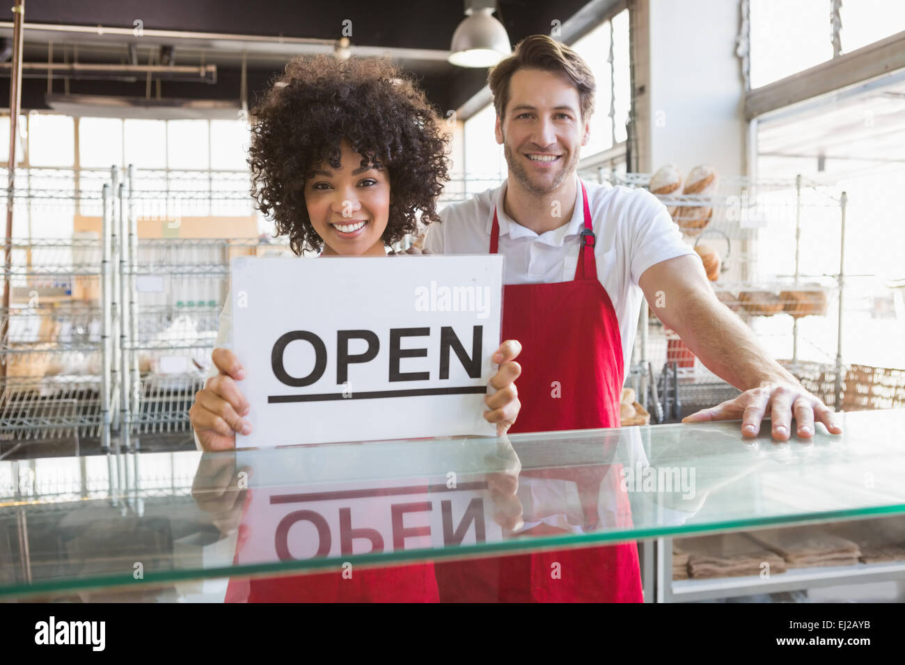Smiling co-workers showing open sign Stock Photo - Alamy