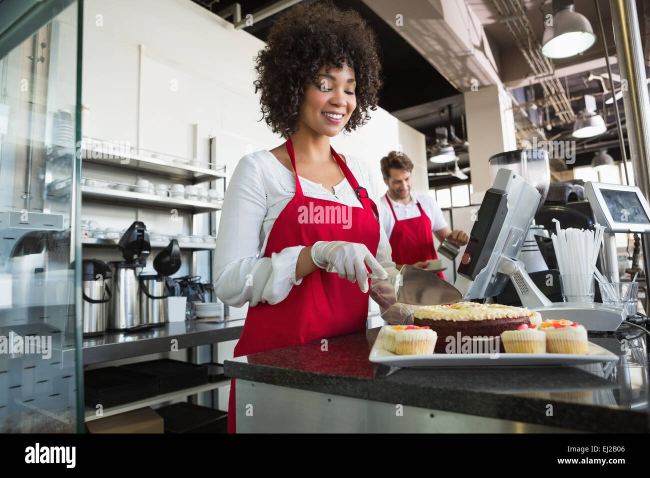 Beautiful waitress in red apron slicing cake Stock Photo - Alamy
