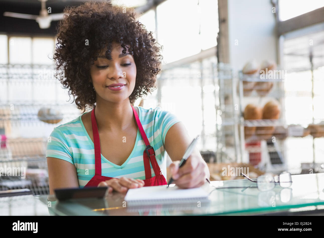 Smiling waitress writing on notepad Stock Photo - Alamy