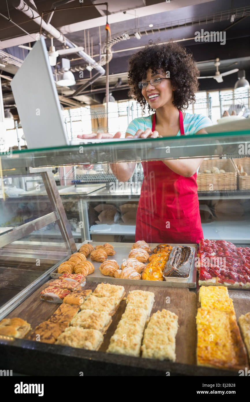 Happy waitress using laptop on counter Stock Photo - Alamy