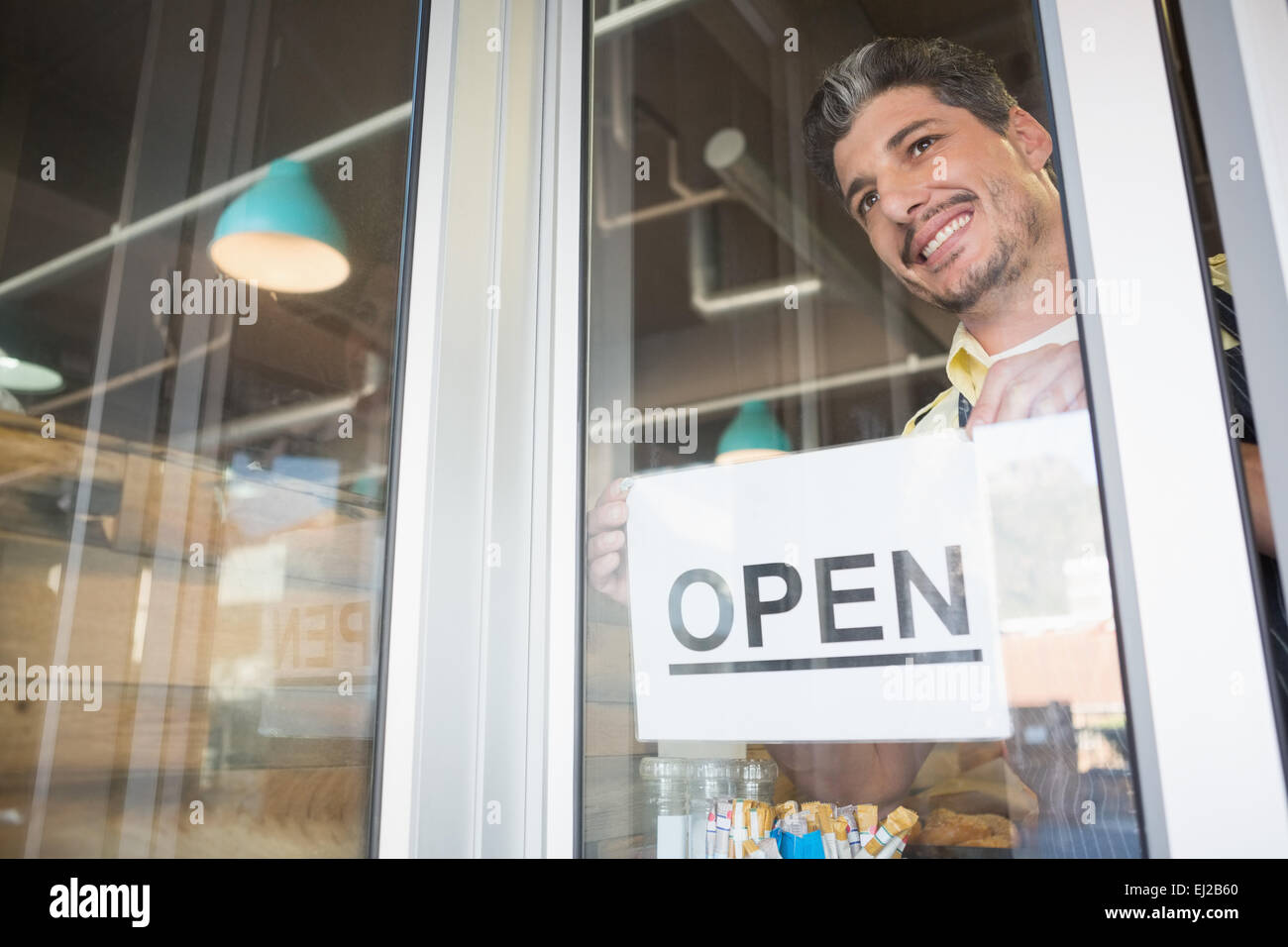 Smiling worker putting up open sign Stock Photo - Alamy