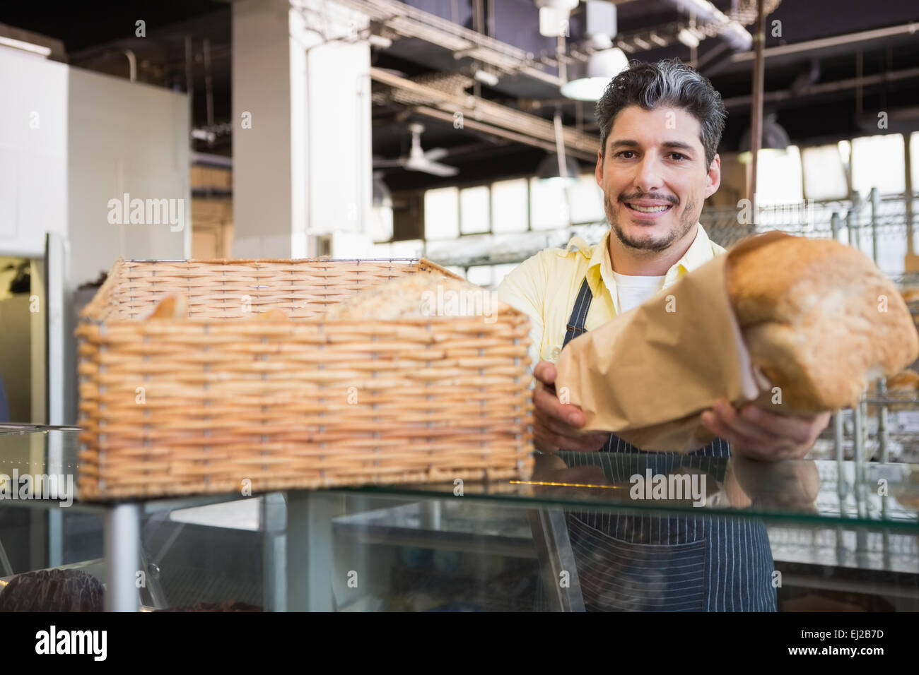 Smiling server in apron offering a bread Stock Photo - Alamy