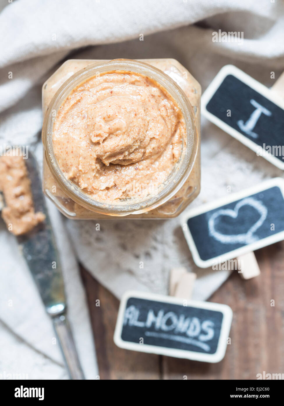 Vertical photo of homemade natural almond butter in a glass jar placed ...