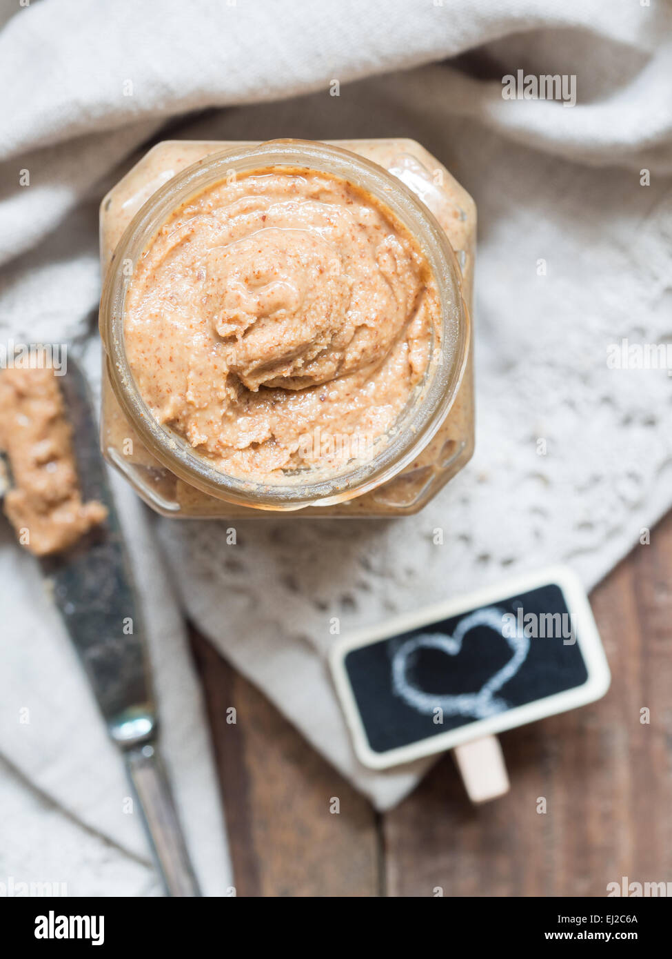 Vertical photo of homemade natural almond butter in a glass jar placed ...