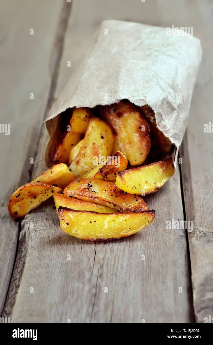 Fried potato wedges in paper bag on rustic table Stock Photo - Alamy